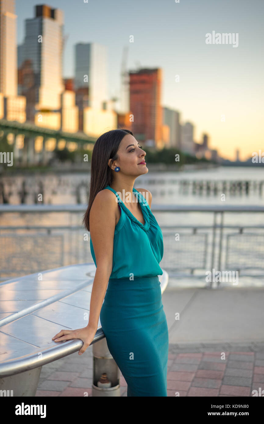 Beautiful girl enjoying sunset in the riverside park with city highrise ...