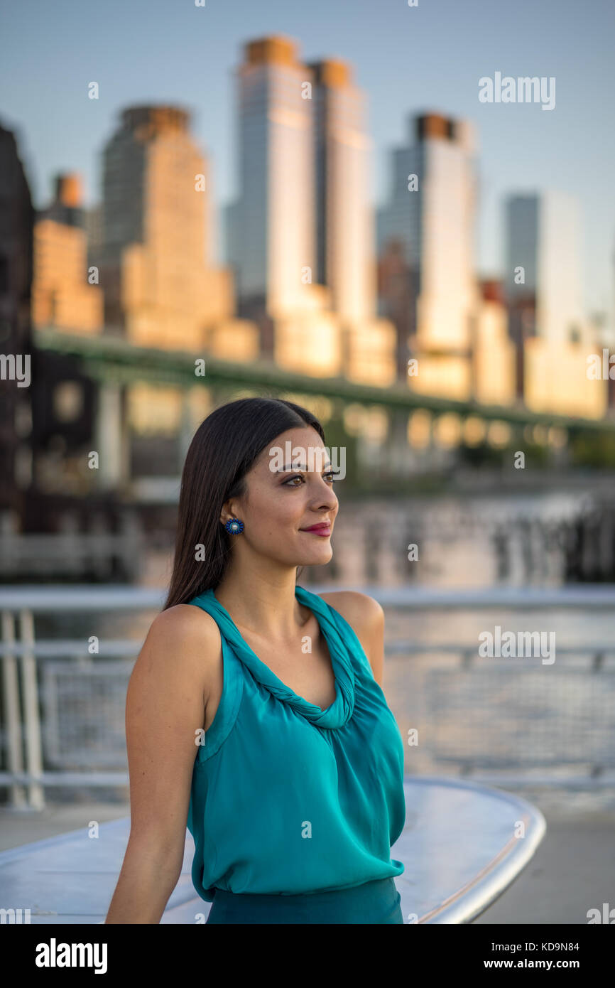 Beautiful girl enjoying sunset in the riverside park with city highrise ...