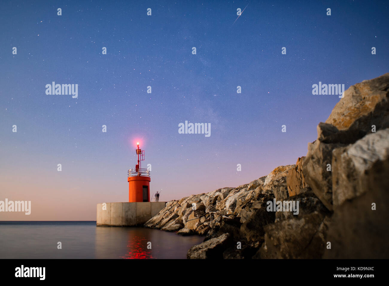 Seascape of a small lighthouse with their reflections on the sea at ...