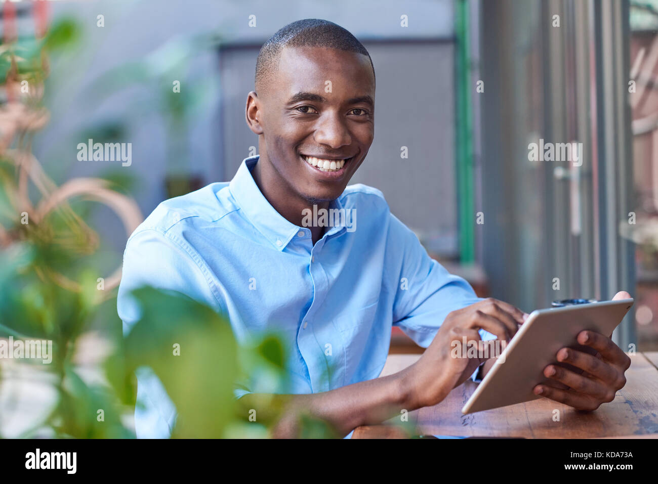 Smiling young African man working online at a sidewalk cafe Stock Photo ...