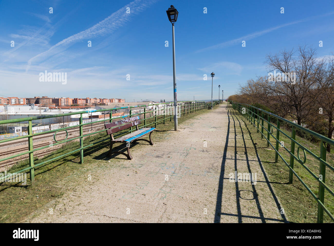 long sunny walkway with wooden benches and metal fences by the train ...