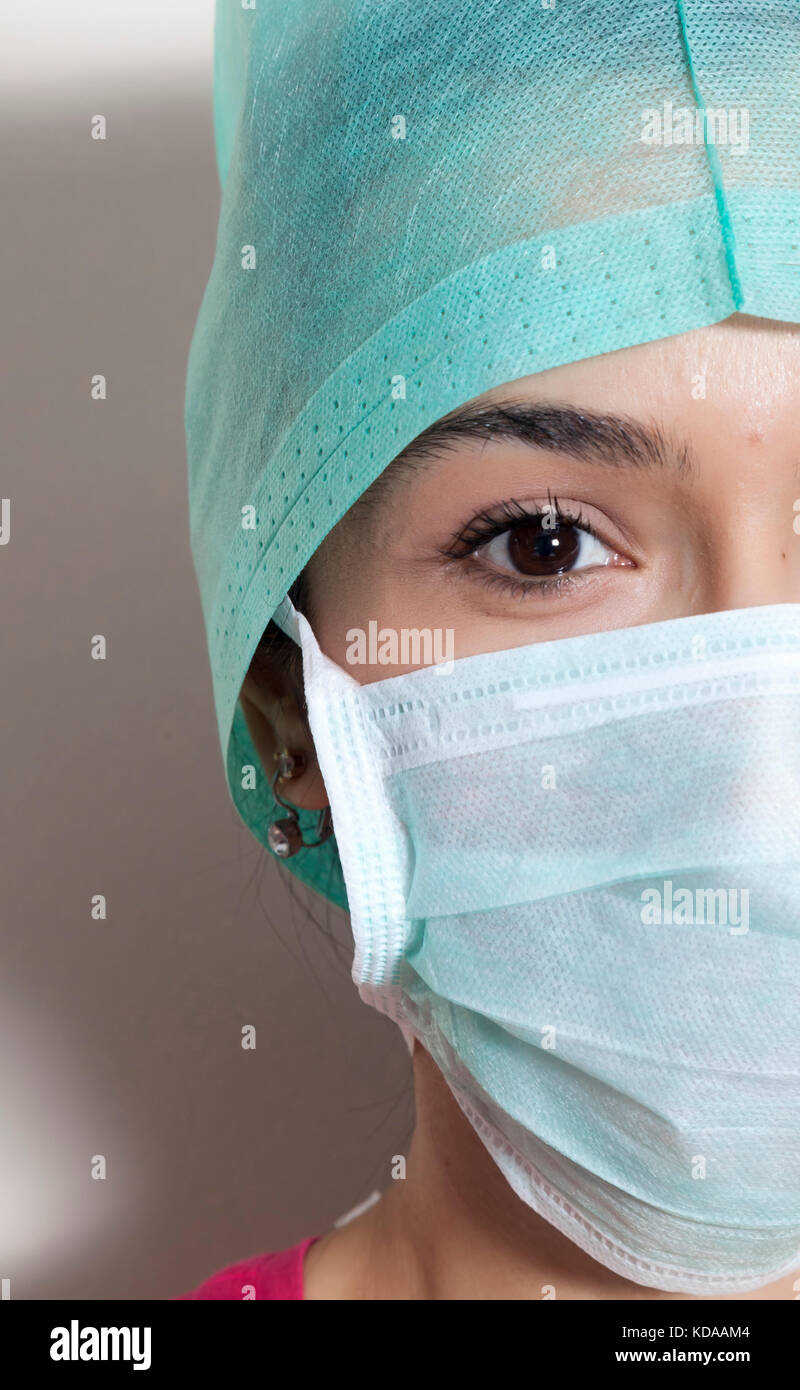Portrait of beautiful young doctor smiling wearing mask and bonnet ...