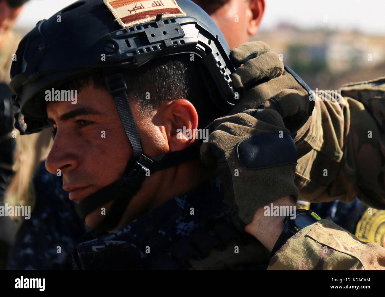 A U.S. soldier helps adjust the helmet of an Iraqi federal police ...