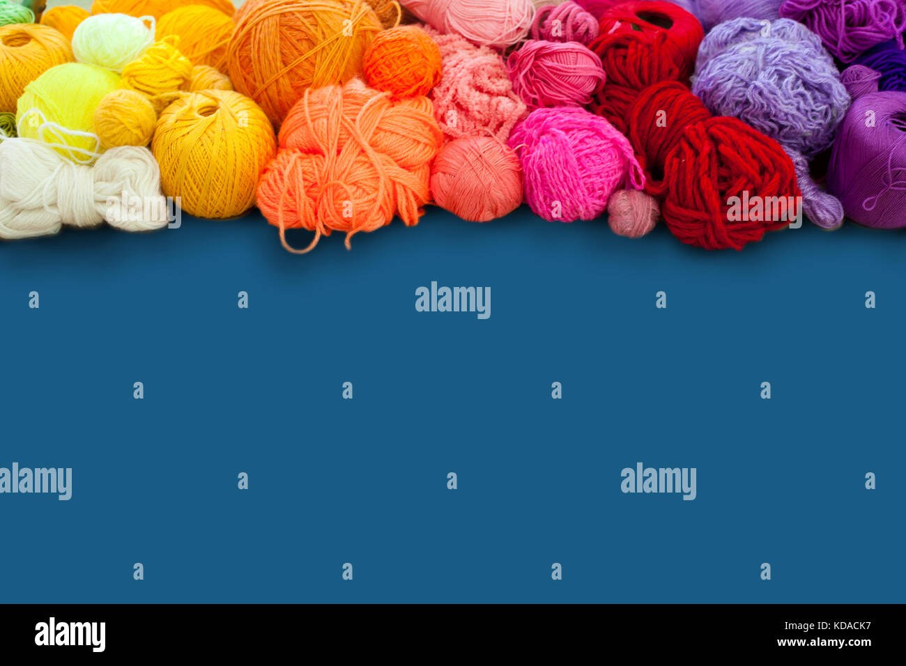 Colorful yarn stacked in a series of colors. Background blue. Balls and ...