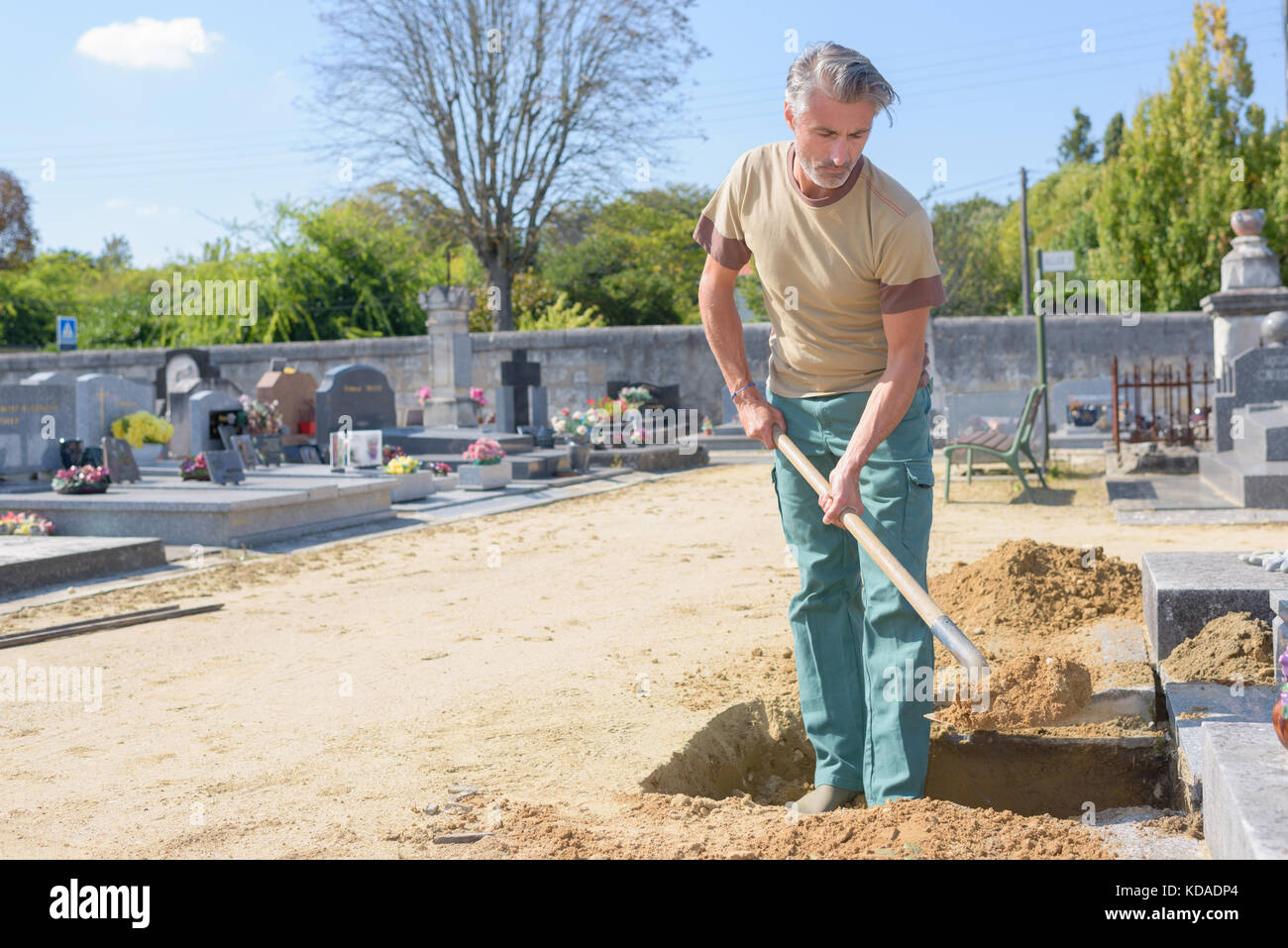 Man shovelling sand into grave Stock Photo - Alamy