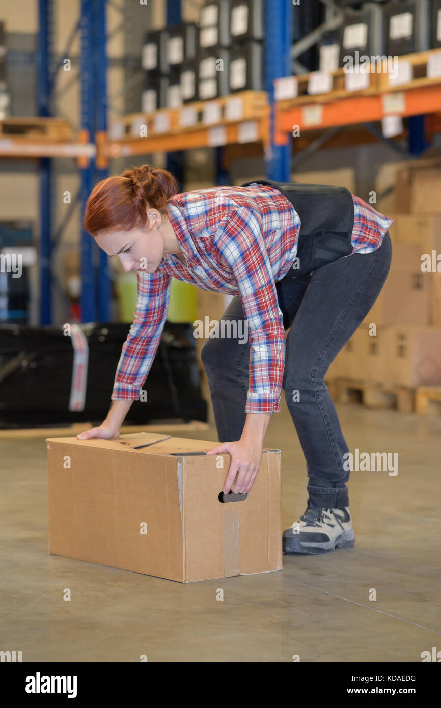 warehouse manager picking up cardboard box in a large warehouse Stock ...