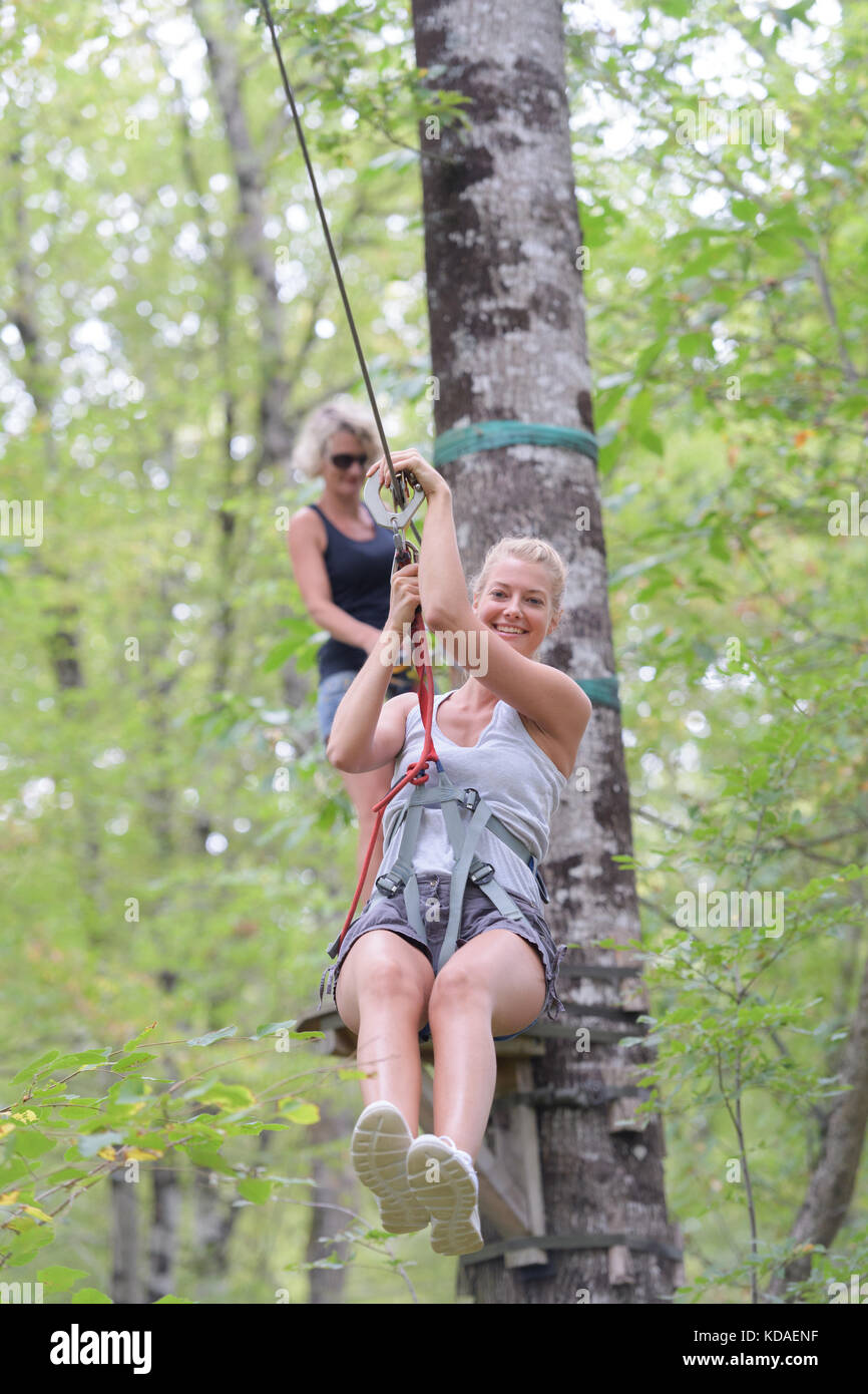smiling woman riding a zip line in the forest Stock Photo - Alamy