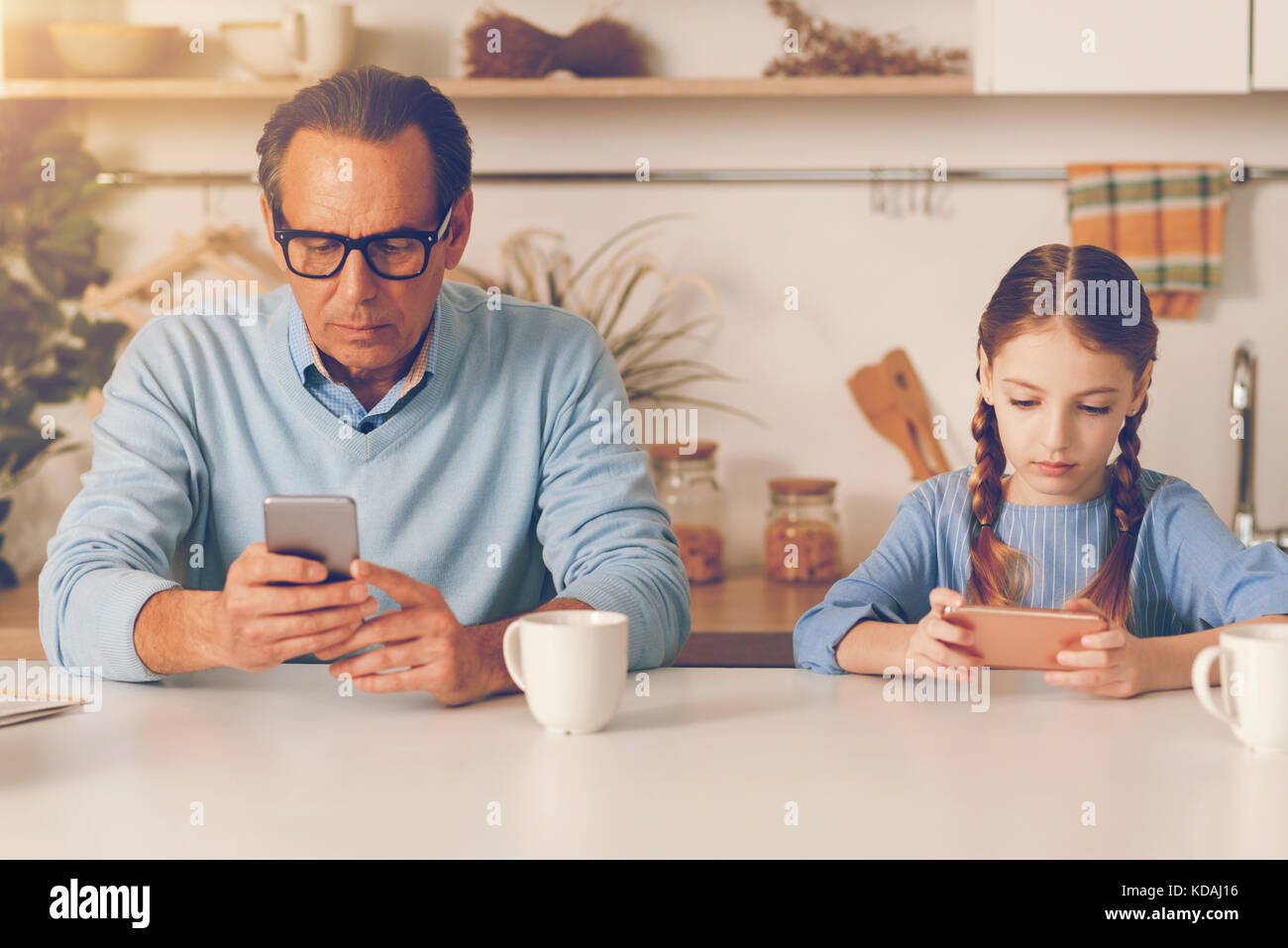 Totally absorbed girl and her dad using smartphones at home Stock Photo ...