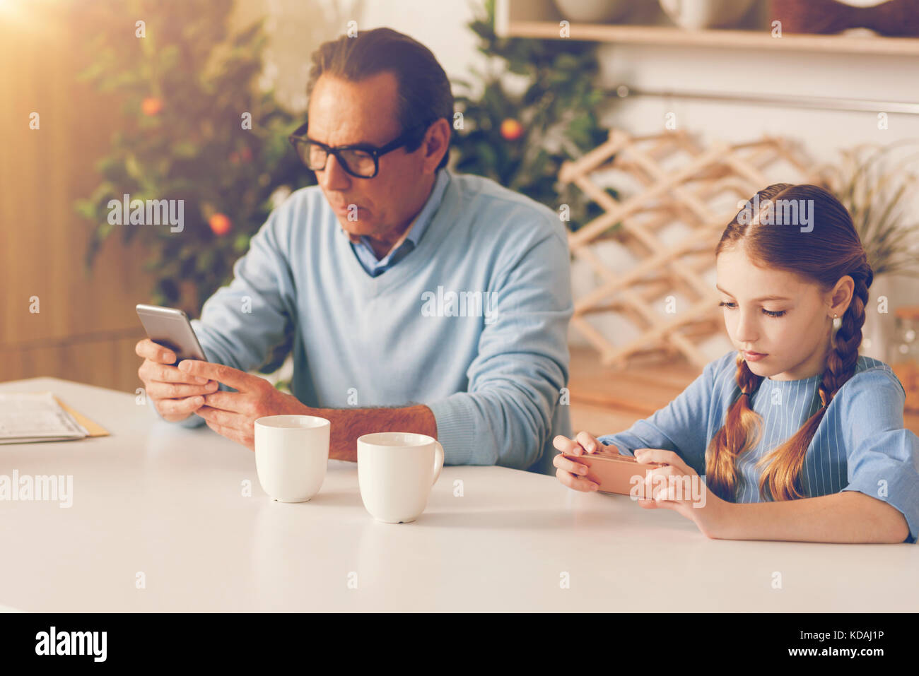 Serious daughter and father with phones ignoring each other Stock Photo ...