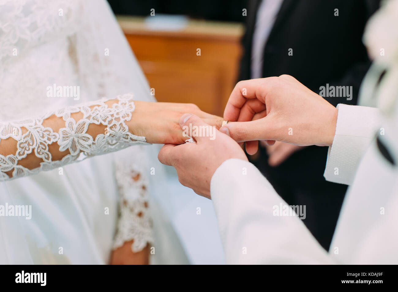 Close-up view of the hand of the groom putting the wedding ring on the ...