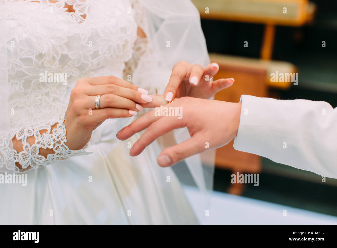 Close-up view of the bride`s hands putting the wedding ring on the ...
