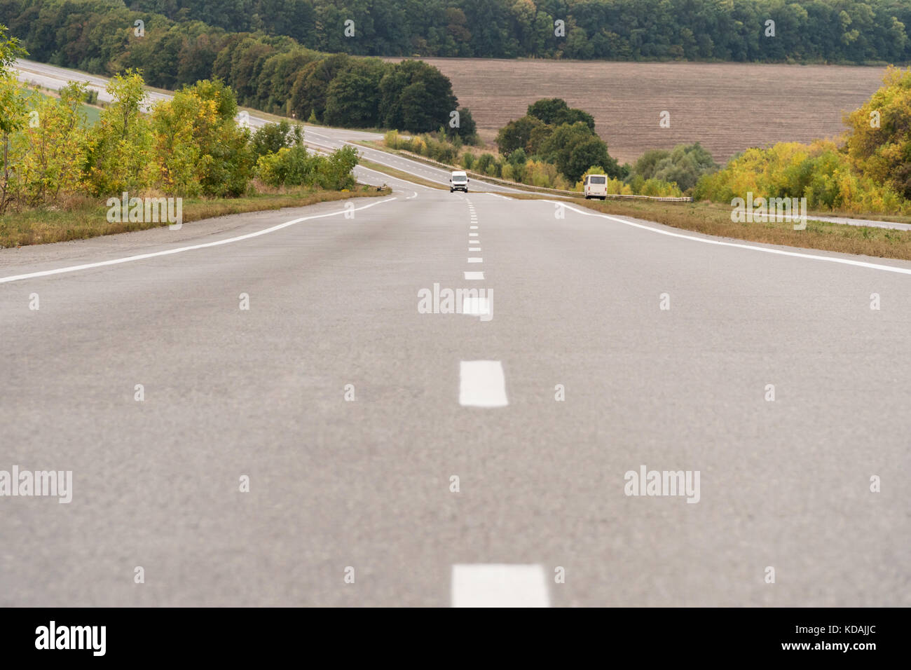 Wide two-lane road among the fields and forests with buses Stock Photo ...