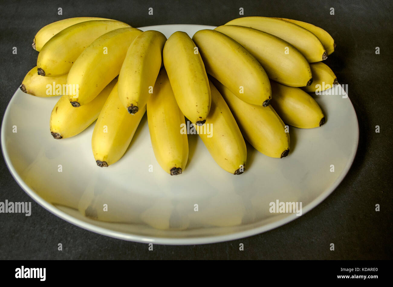 Fan-shaped bunch untreated ripe small bananas on white dish Stock Photo ...