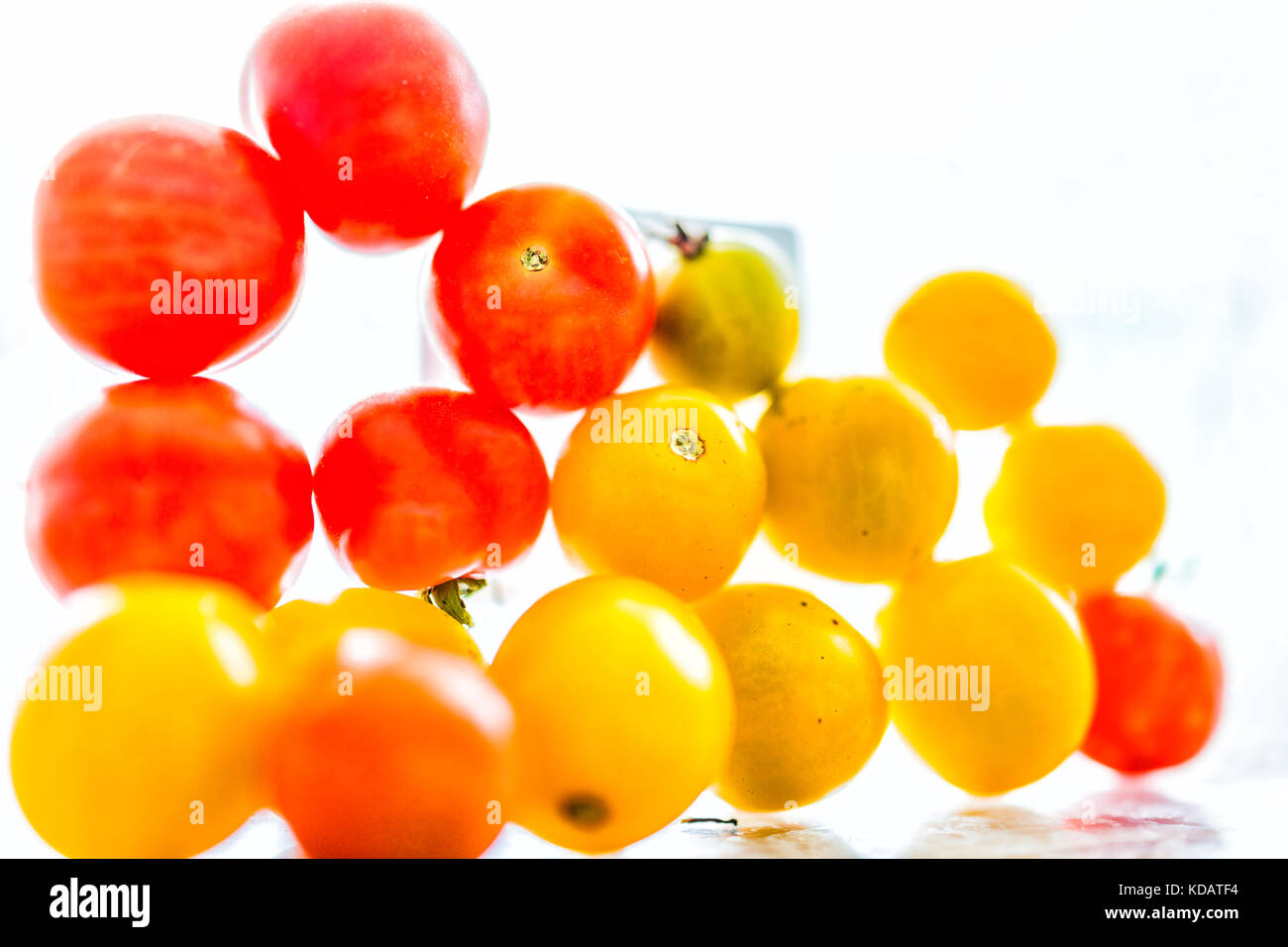 Stack of small cherry colorful tomatoes in a plastic container isolated ...