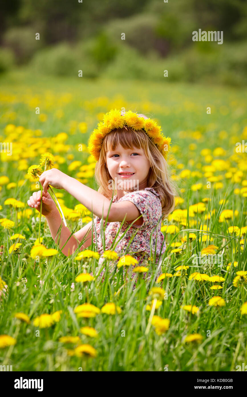Portrait of cute little girl with dandelion wreath enjoying a summer ...
