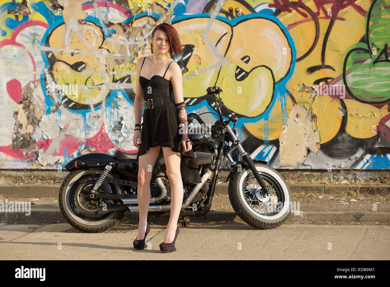 Pretty girl in a short black dress and high heels with a motorcycle ...