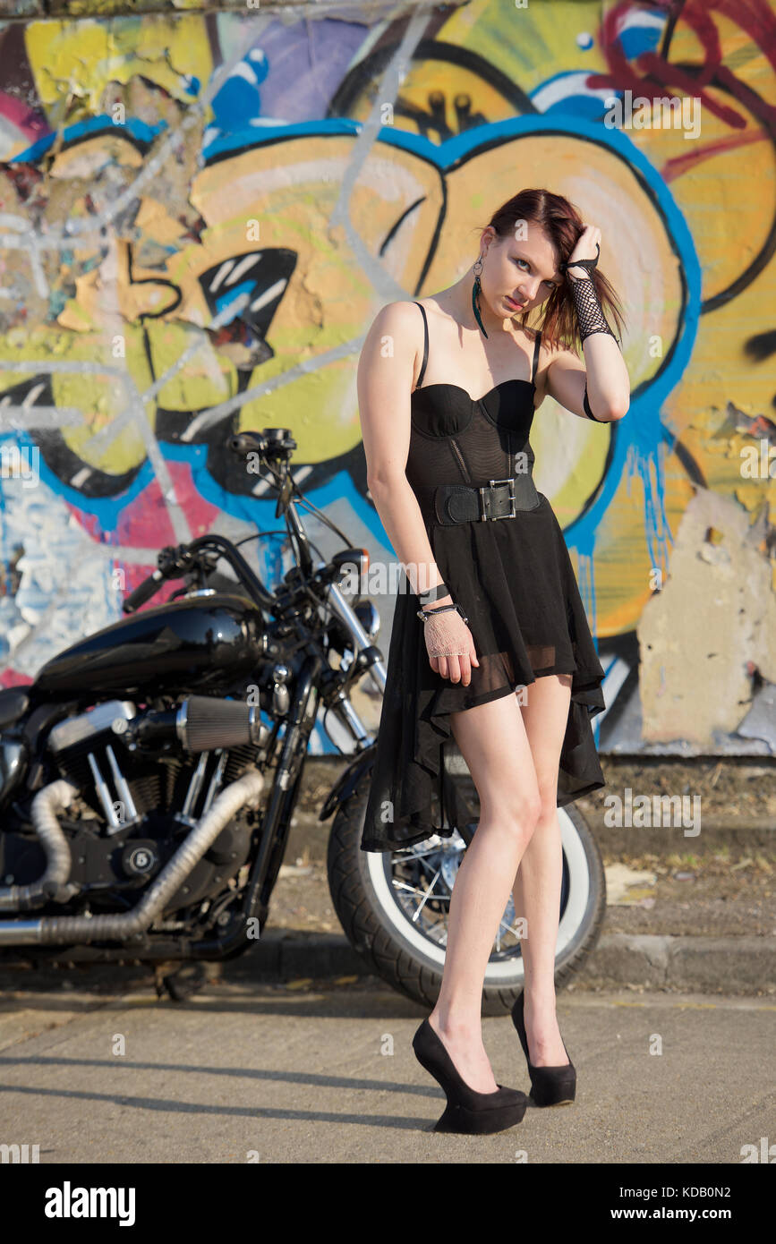 Pretty girl in a short black dress and high heels with a motorcycle ...