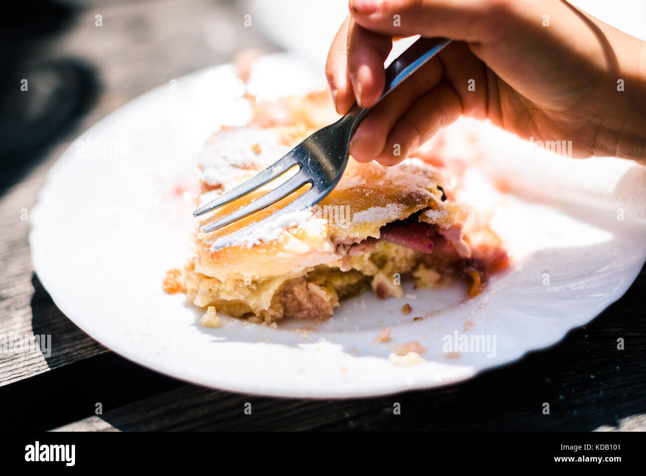 Children eating cheese and cherry strudel with sugar on top. Child's ...