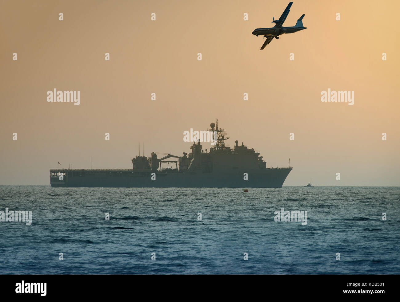 Airplane flying over warship in early morning Stock Photo - Alamy