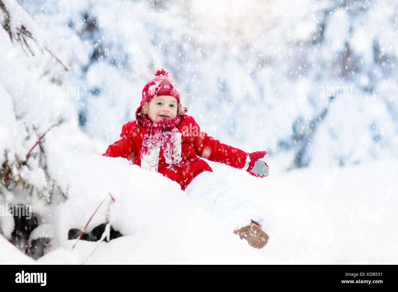 Child playing with snow in winter. Little boy in colorful jacket and ...