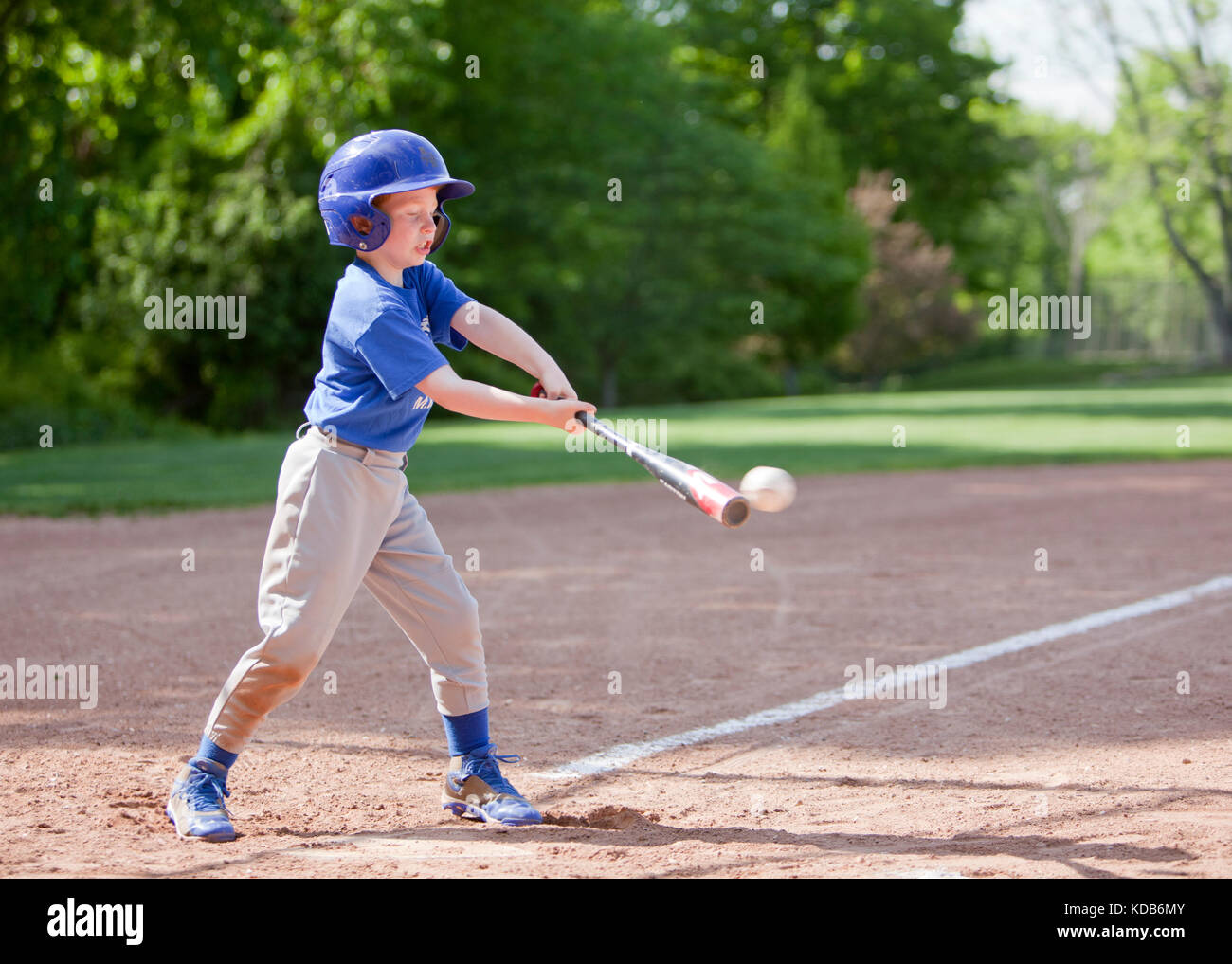 Boy hitting ball whilst playing baseball in a blue uniform Stock Photo ...