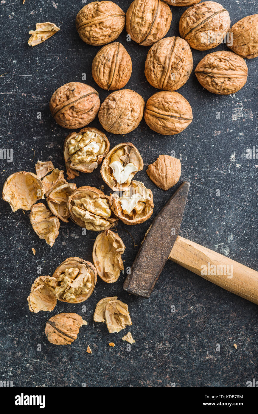 Tasty dried walnuts and hammer on old kitchen table. Top view Stock ...
