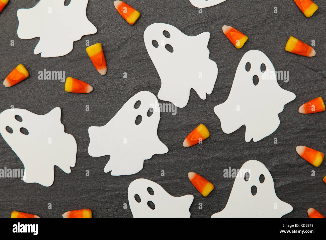 Halloween background with ghosts and candy corn on a slate background ...
