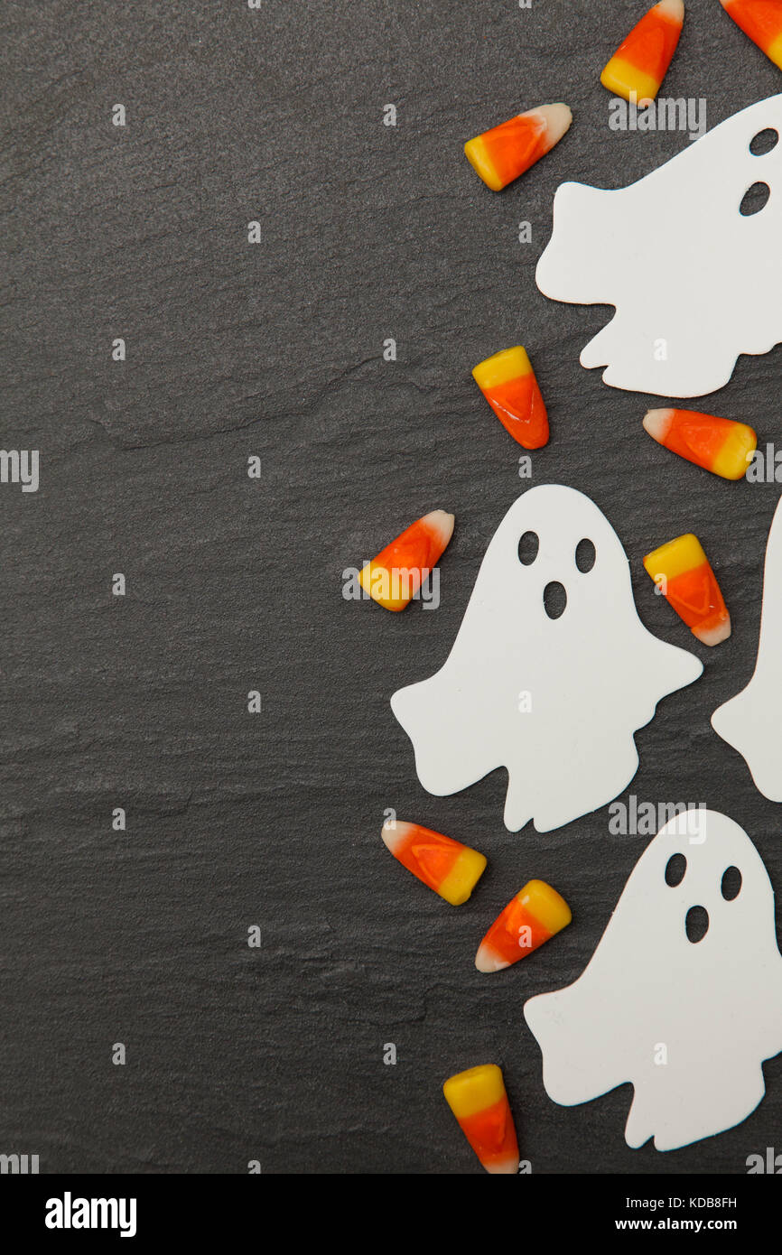 Halloween background with ghosts and candy corn on a slate background ...