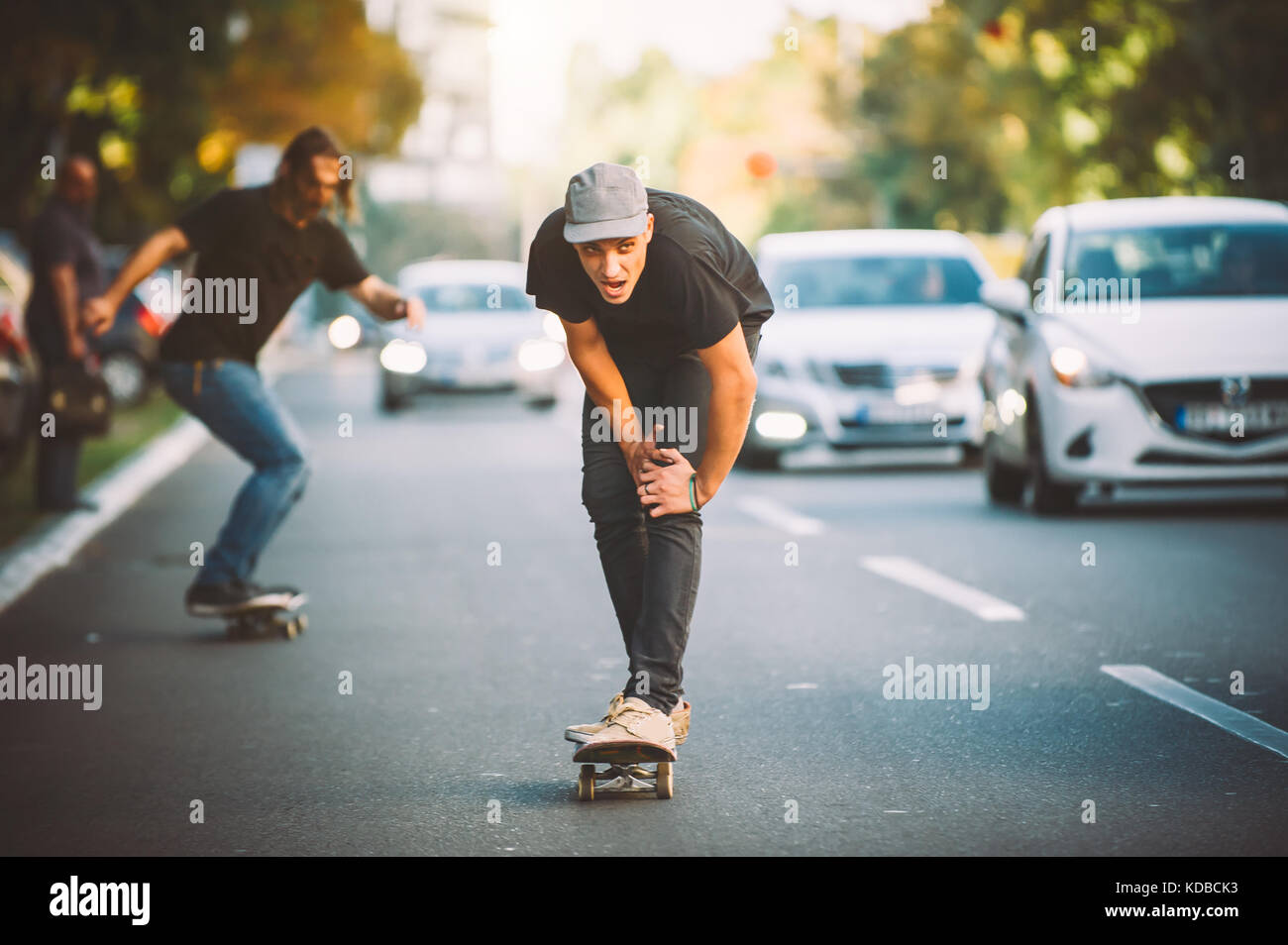 Two pro skateboard rider ride skate in front of the car on the city ...