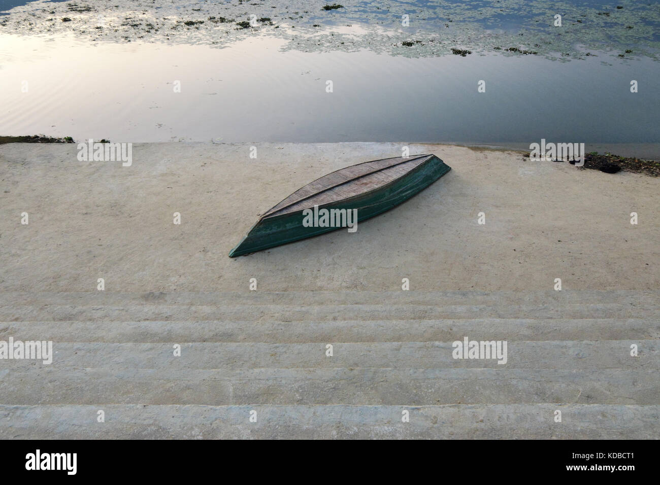An inverted boat on a concrete embankment on the shore of a mountain ...