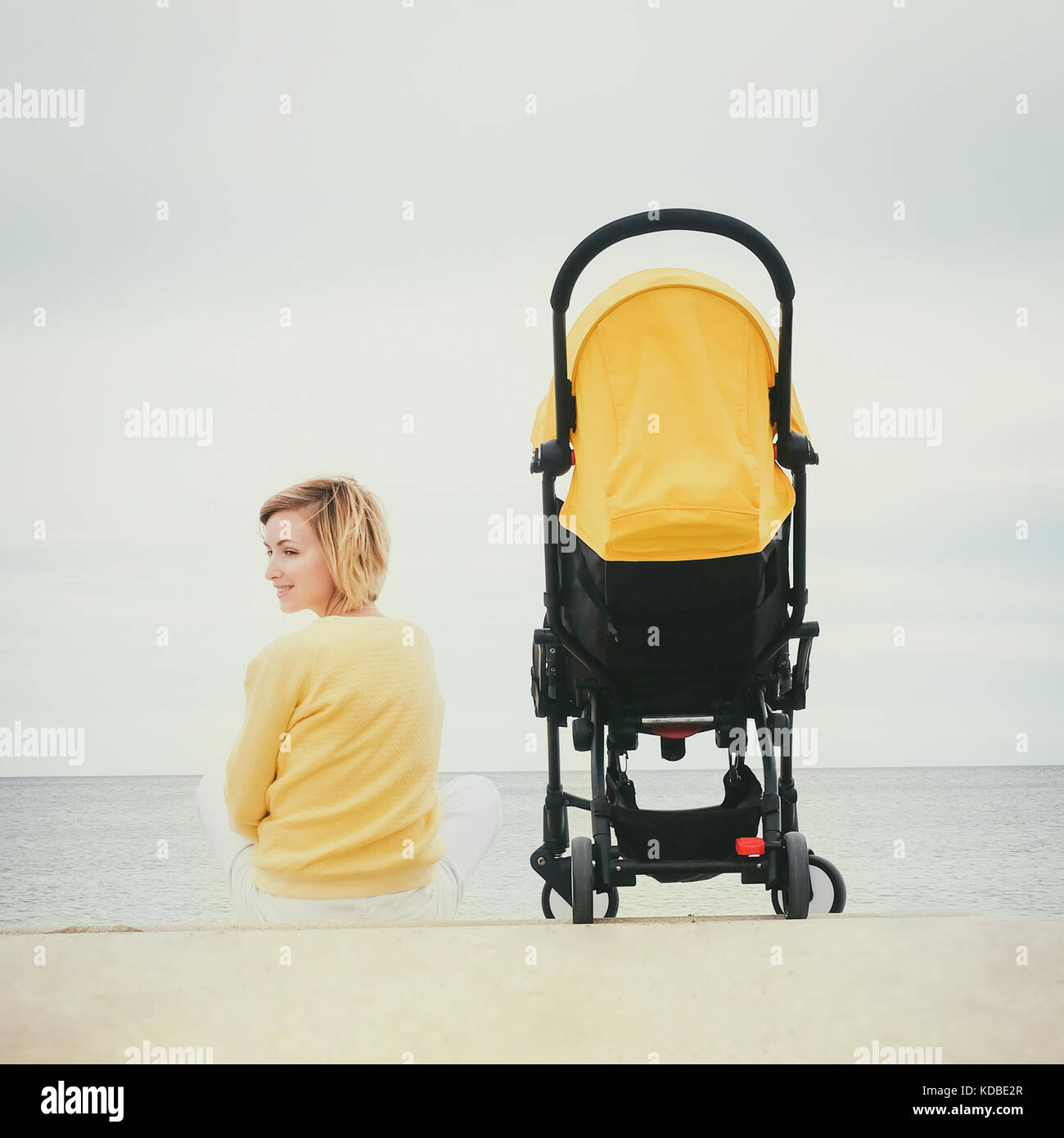 Rear view of young mother sitting with baby stroller Stock Photo - Alamy