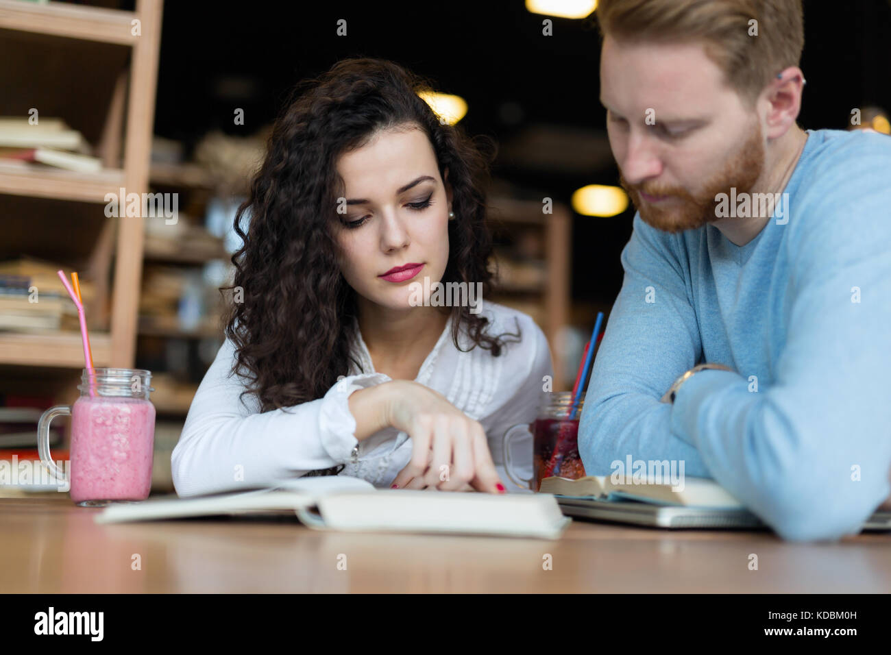 Young students spending time in coffee shop reading books Stock Photo ...