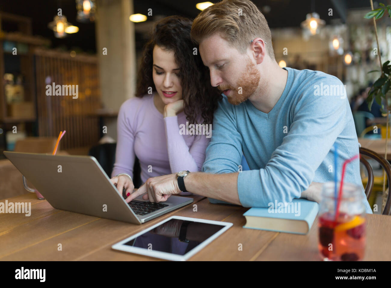 Happy couple spending time at coffee shop working on laptop Stock Photo ...