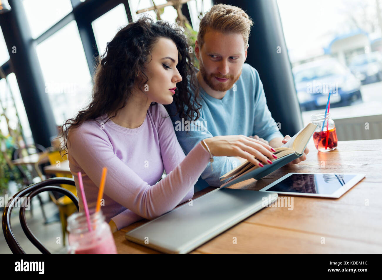Portrait of young students reading book and talking Stock Photo - Alamy