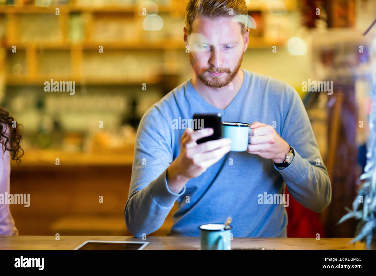 Handsome man using mobile phone in coffee shop Stock Photo - Alamy