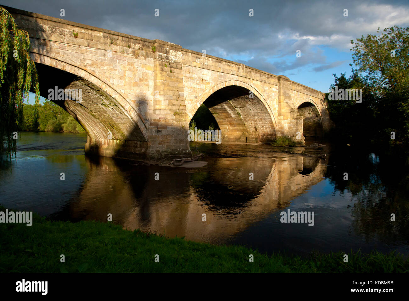 sun falling on stone bridge with a heavy grey clouds and blue sky ...
