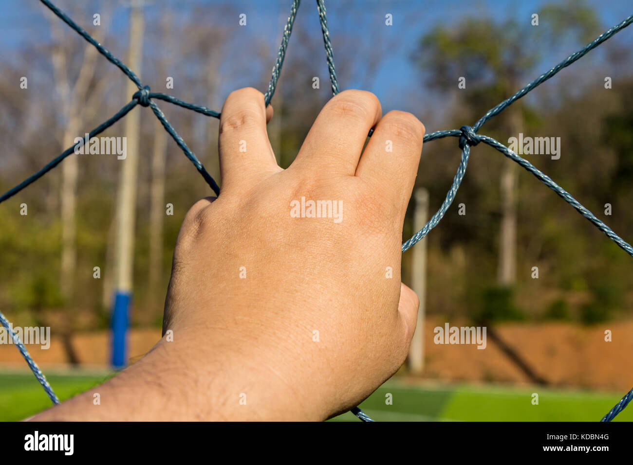 Hand grab the rope mesh fence Stock Photo - Alamy
