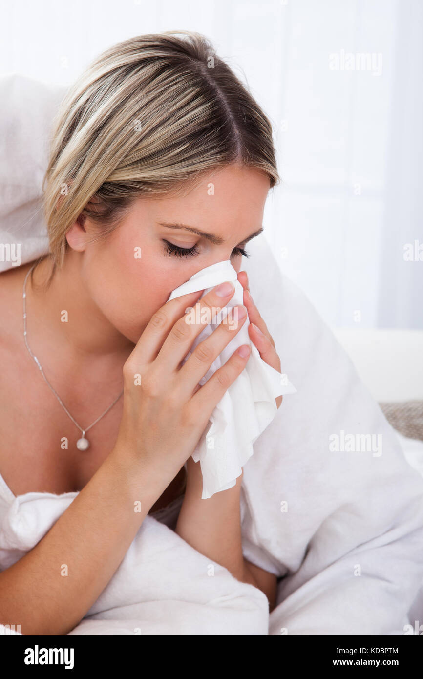 Infected woman blowing his nose in tissue paper Stock Photo - Alamy
