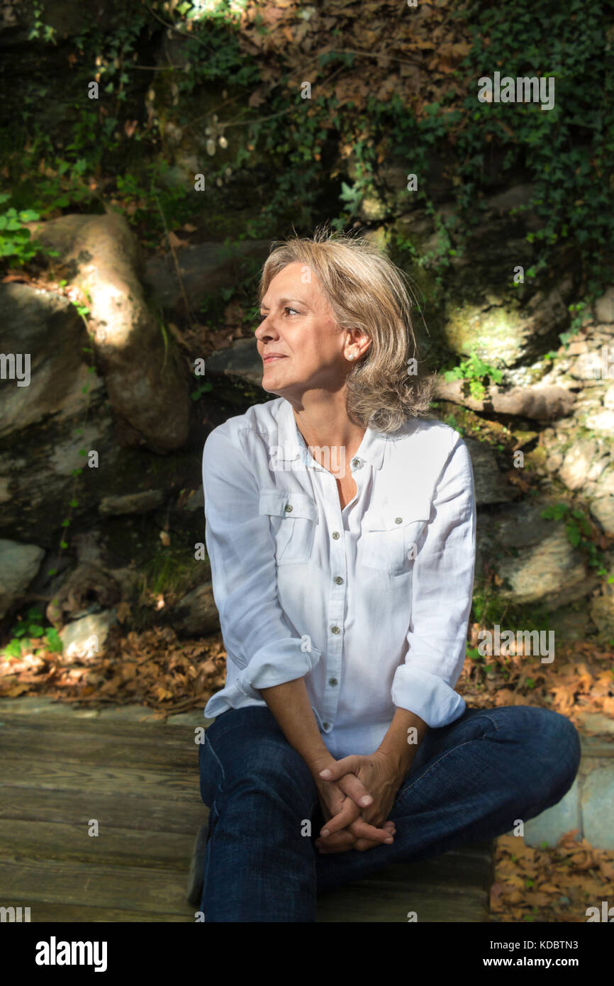 Senior woman, 61 years old, wearing a shirt and jean, autumn season ...