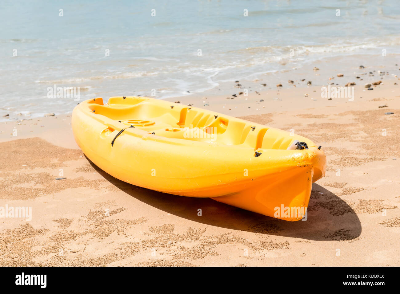 close-up of a yellow kayak at the water's edge on the sandy beach of ...