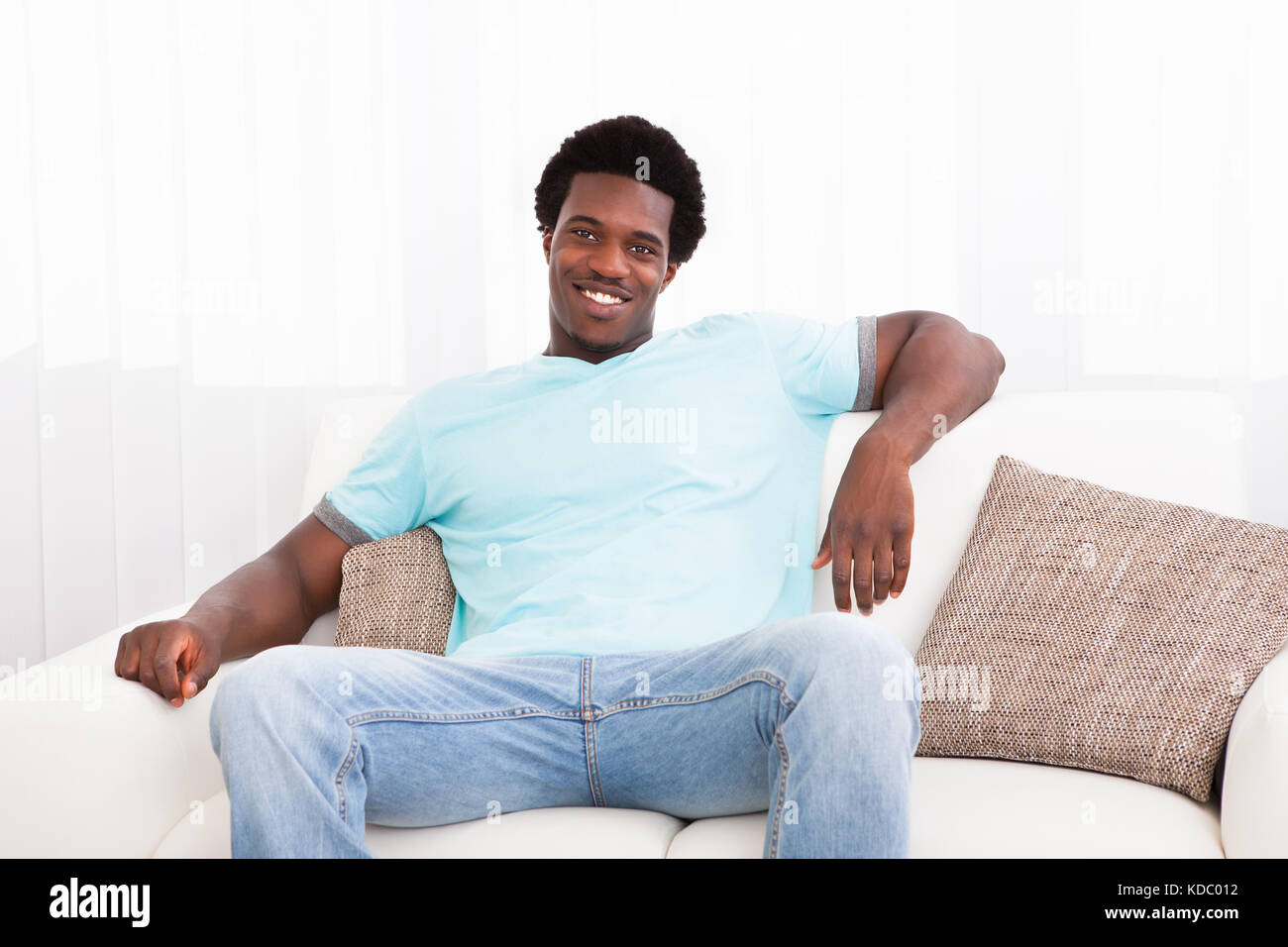 Happy Relaxed Young African Man Sitting On Couch Stock Photo - Alamy