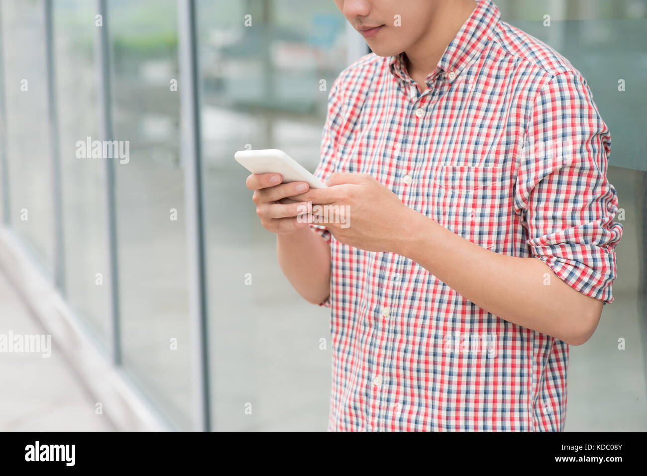Happy asian man smiling as he reads a text message standing outside the ...