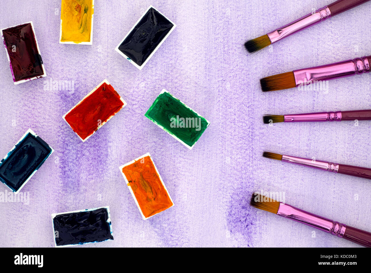 Paintbrushes and watercolor cuvettes on purple hand drawing backgrounds ...