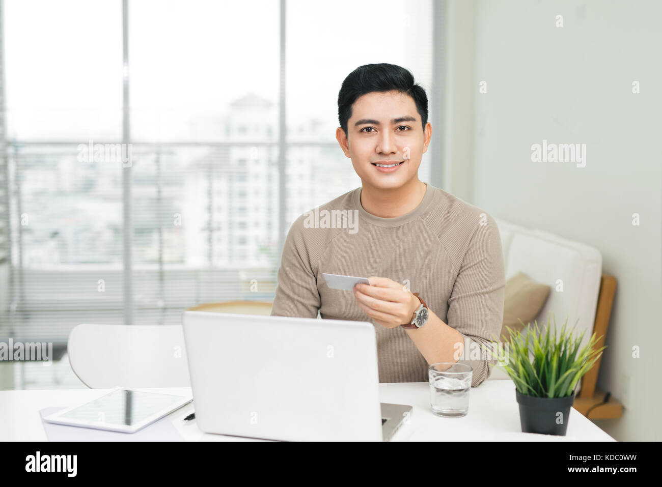 Portrait of a casual smiling young man make payment using credit card ...