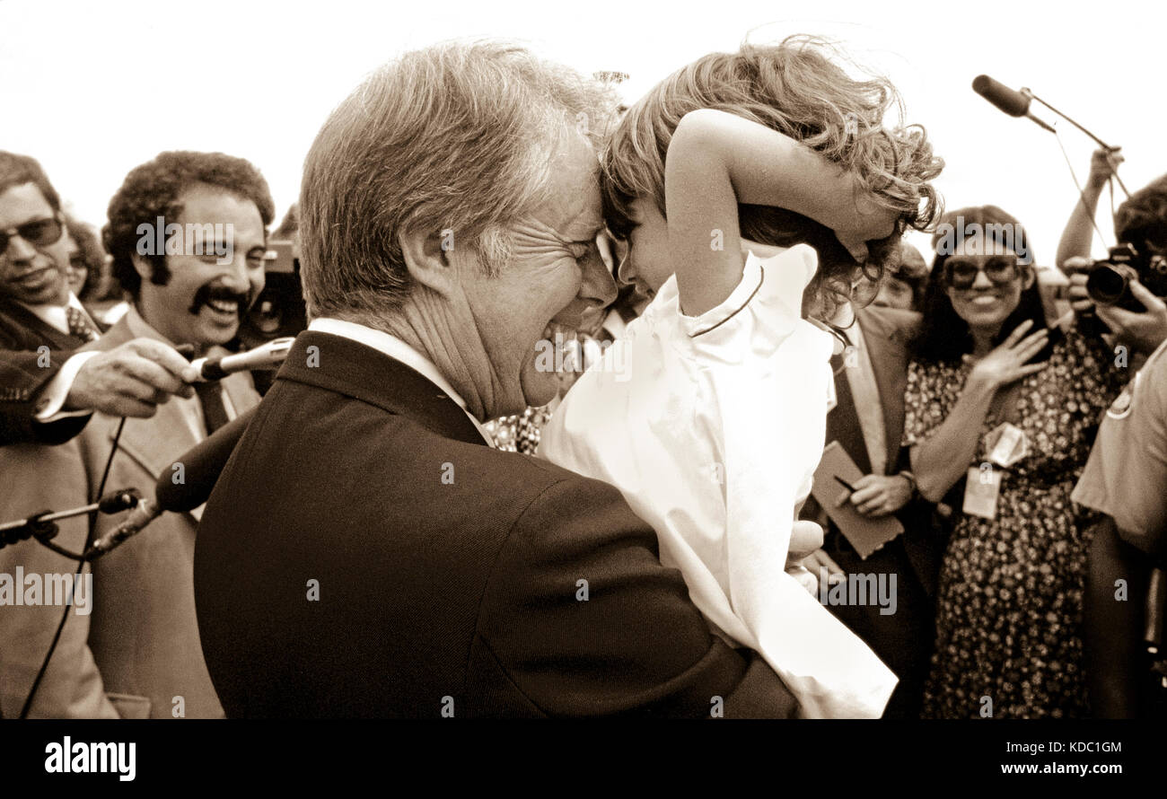 A charmed White House press corps looks on as President Carter rubs noses with a child Stock ...