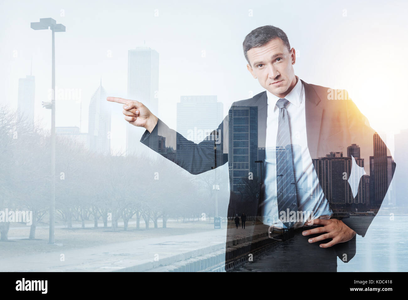 Strict man in a smart black suit pointing to the right Stock Photo - Alamy