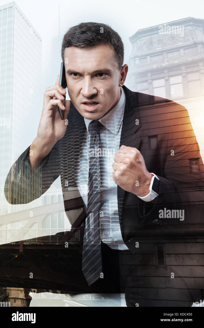 Serious angry man making a fist while talking on the phone Stock Photo ...