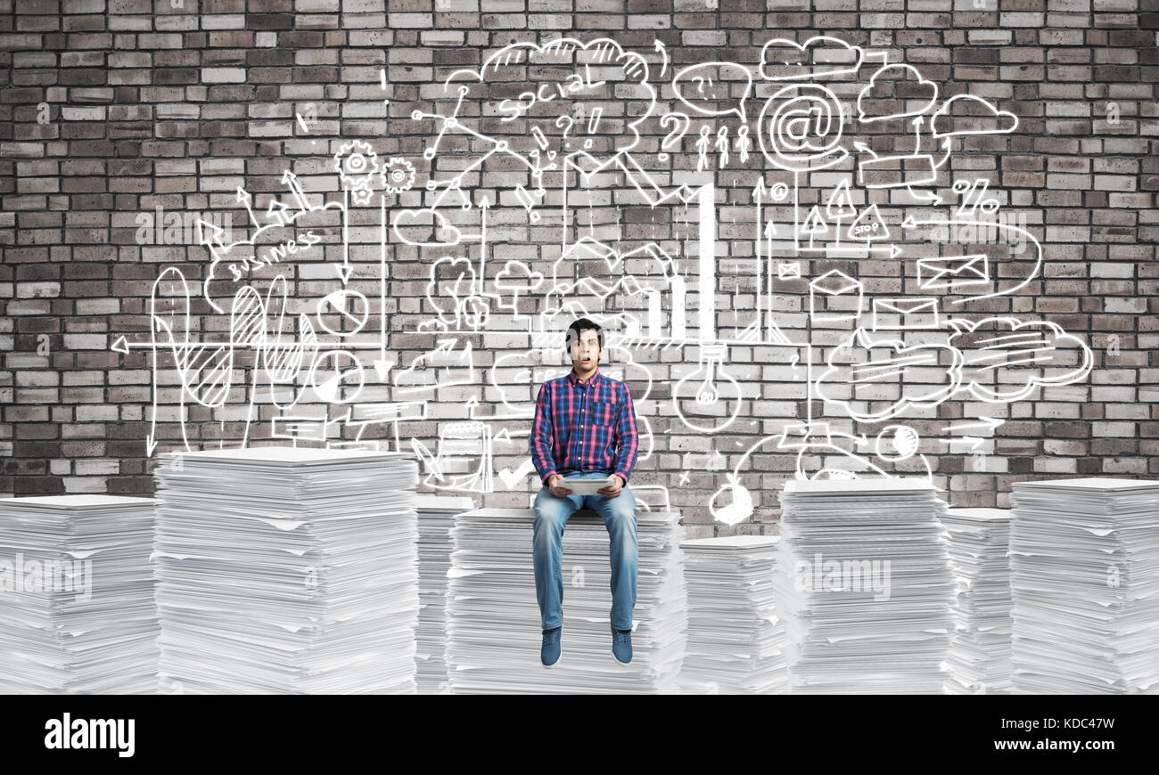Attractive man sitting on pile of paper documents Stock Photo - Alamy