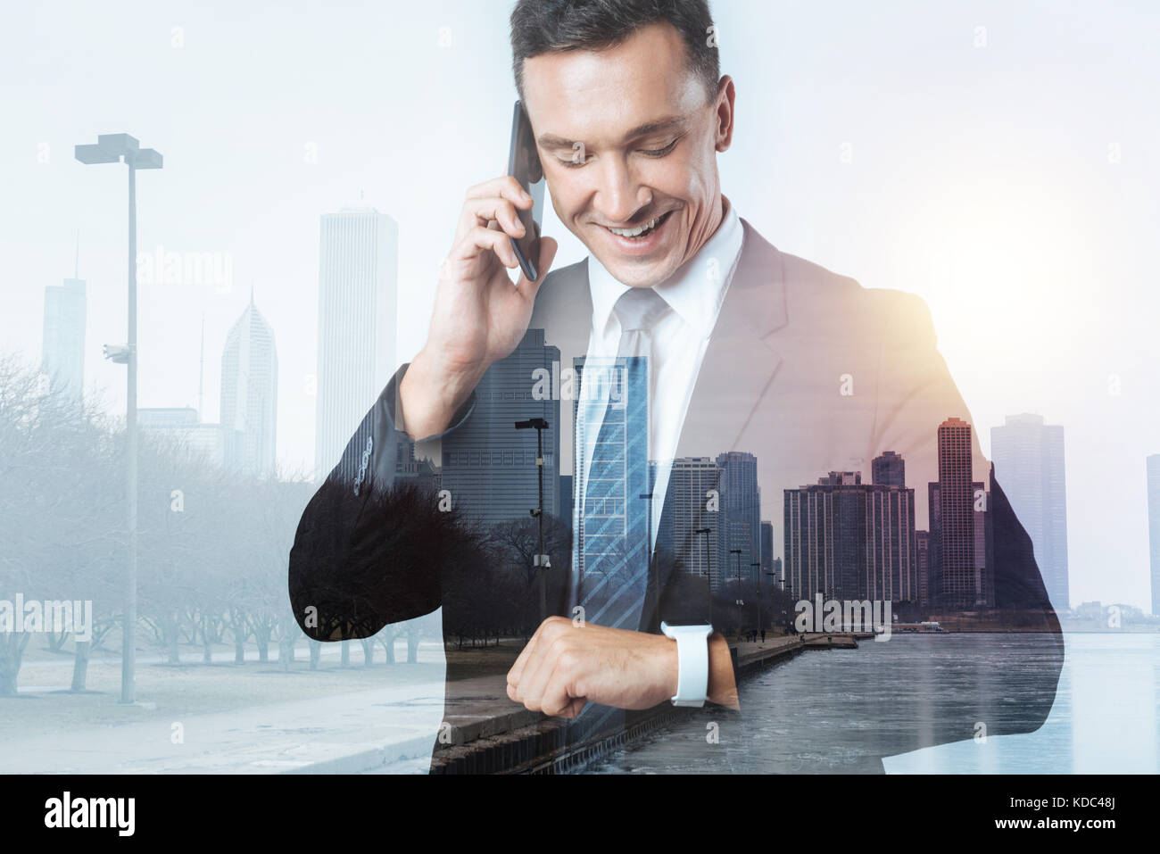Happy man checking time while talking on the phone Stock Photo - Alamy
