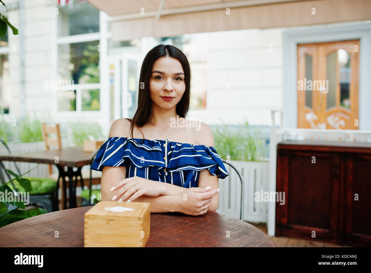Gorgeous brunette girl sitting on the table in cafe Stock Photo - Alamy